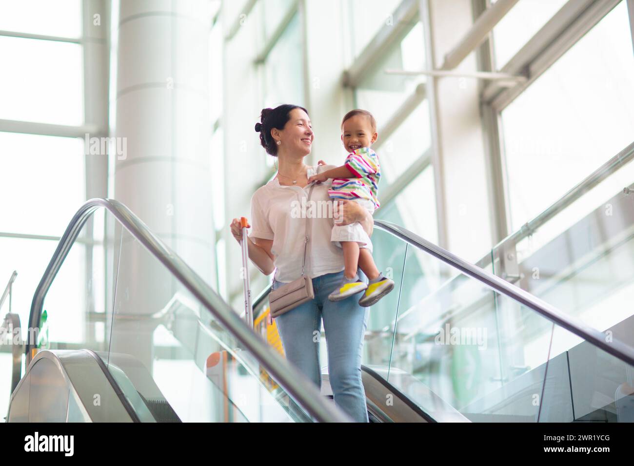 Family in airport. Young Asian mother and child travel by air. Fly with ...