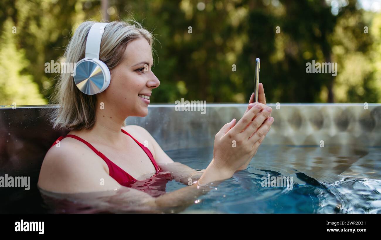 Rlaxed woman wearing headphones listening to music and sitting in hot ...