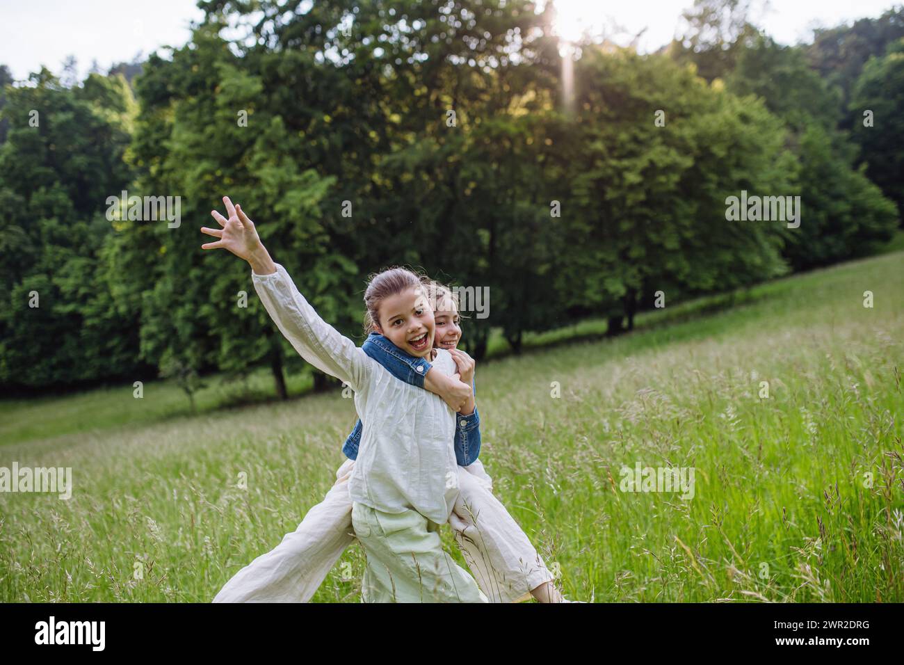 Two sisters playing at meadow in grass, having fun, running a laughing ...