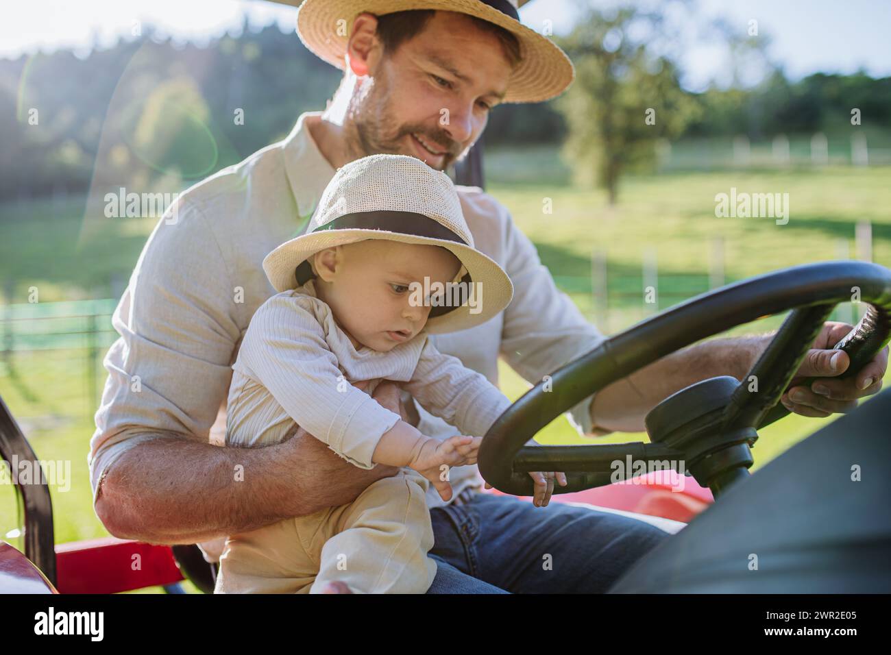 Farmer father riding tractor with his little baby son. Baby growing up ...