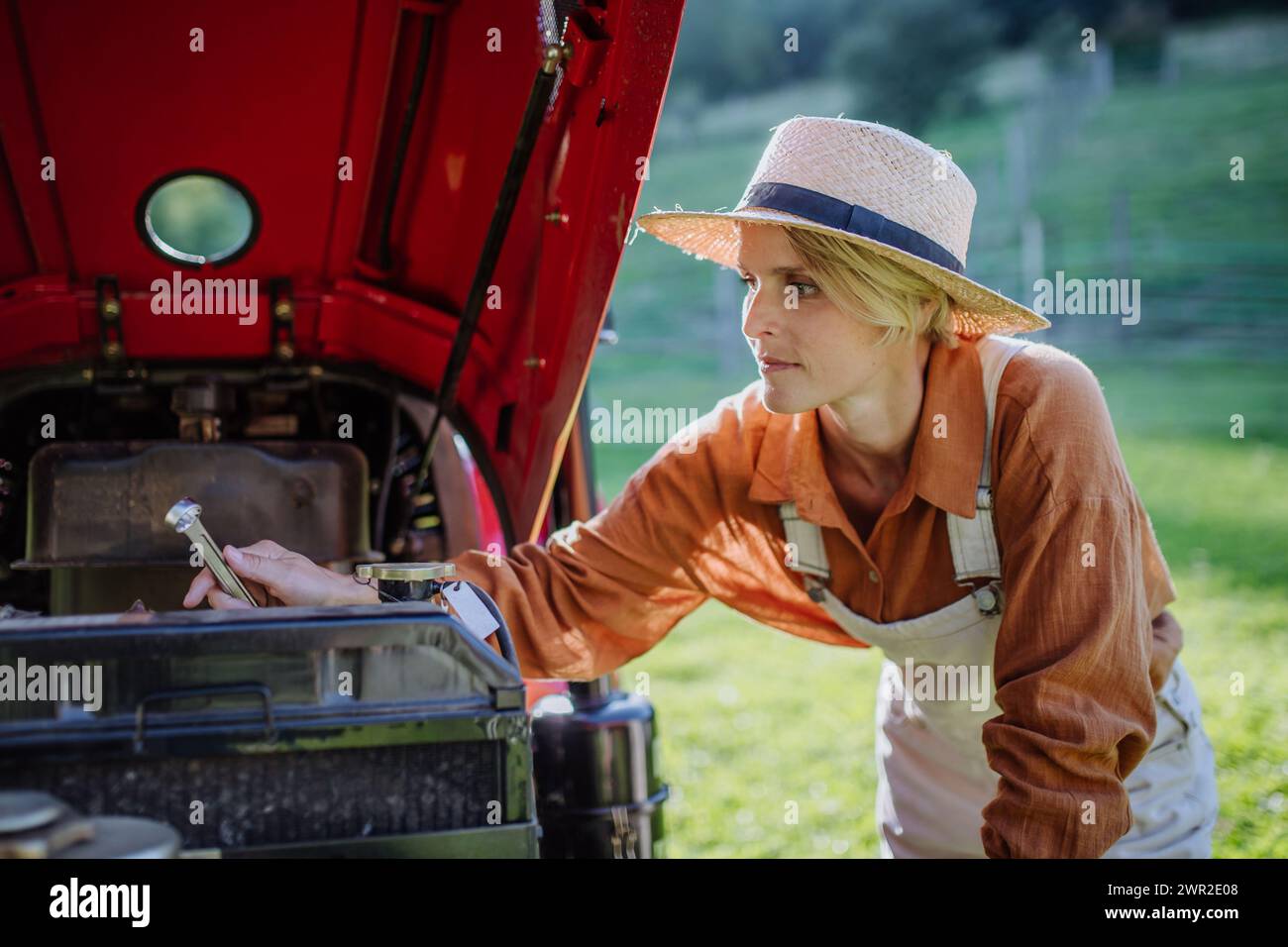 Female farmer fixing tractor, tractor maintenance. Progressive farmer ...