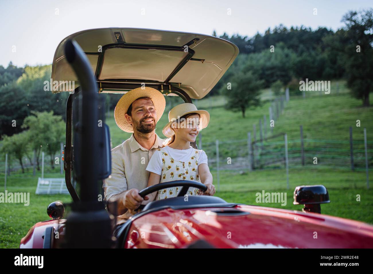 Farmer father riding tractor with his daughter. Girl growing up on ...