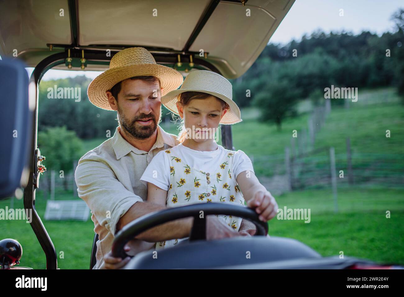 Farmer father riding tractor with his daughter. Girl growing up on ...