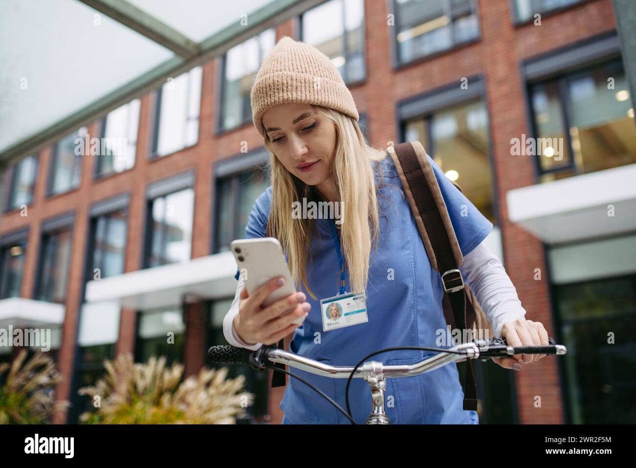 Beautiful nurse commuting through the city by bike. Doctor city commuter traveling from work by ...