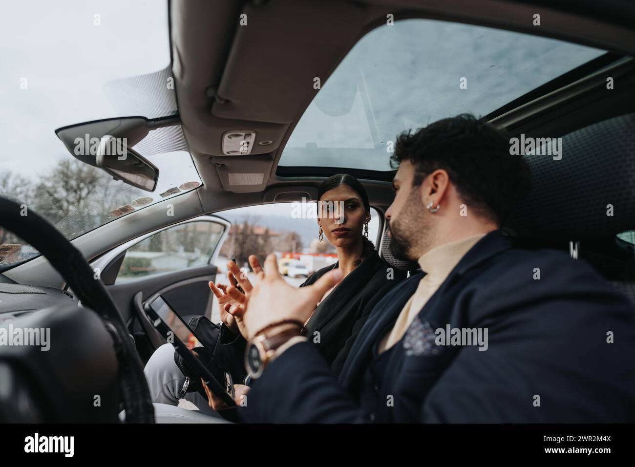 Business colleagues having a conversation in a car during a commute ...
