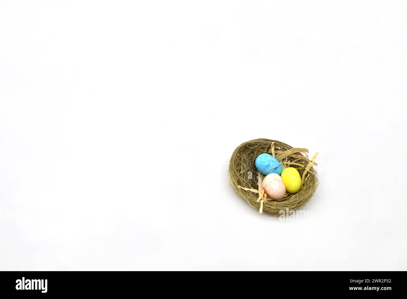 Small model nest with three coloured eggs isolated on a white ...