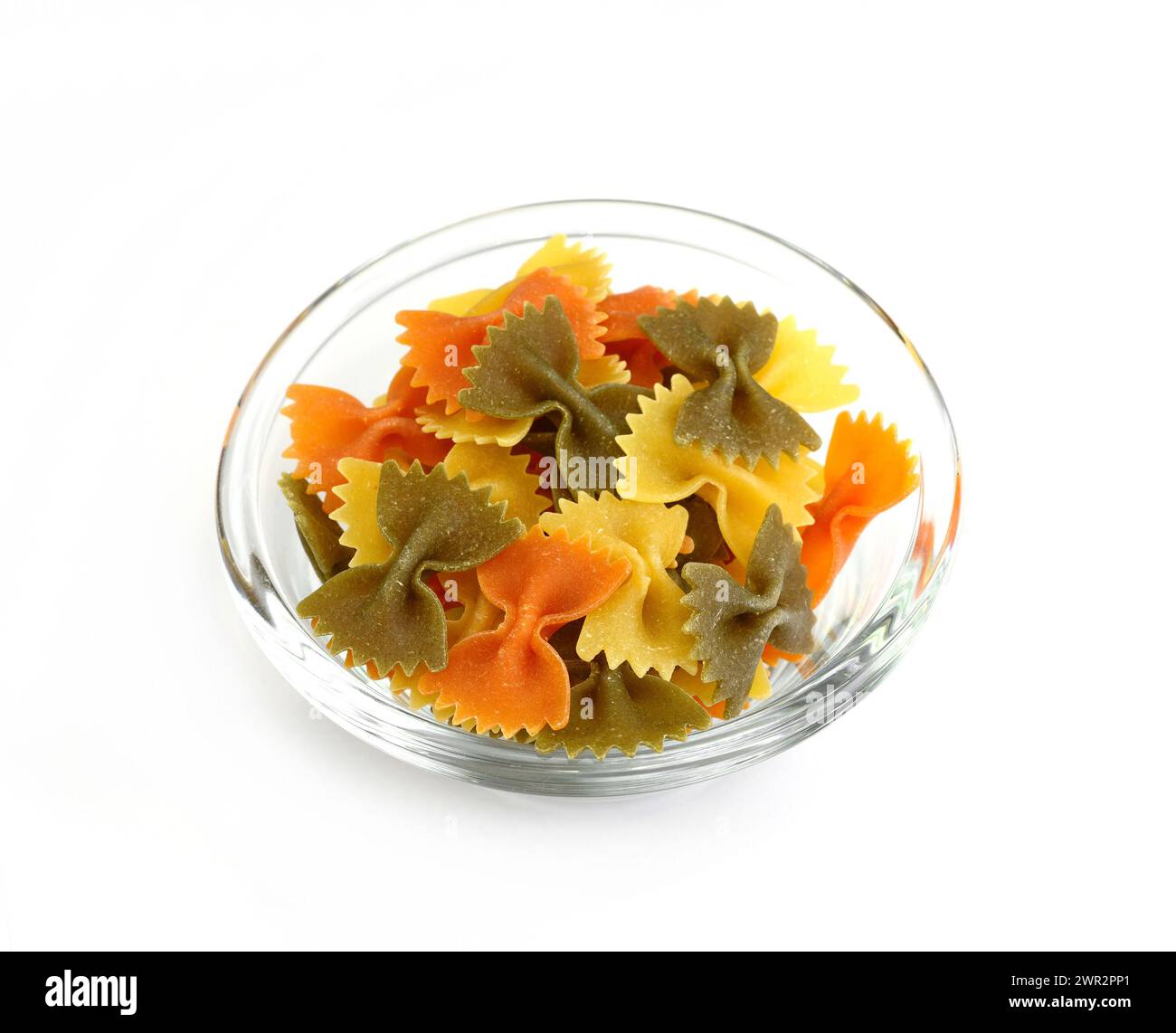 Color pasta in the form of bows in a bowl, isolated. Raw farfalle with ...