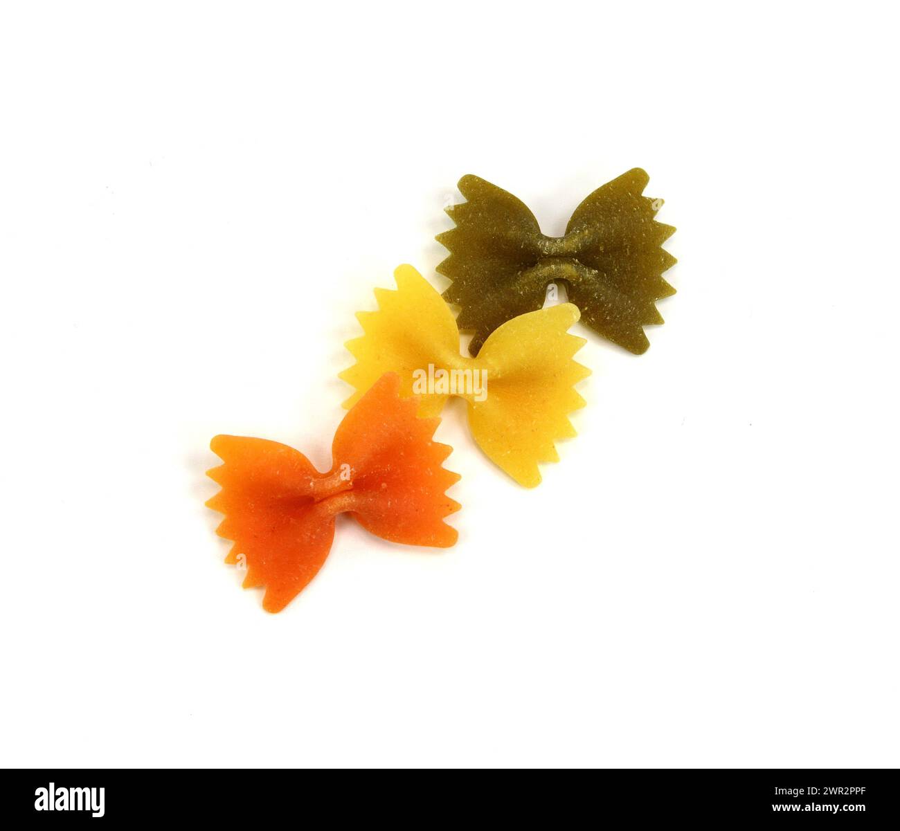 Color pasta in the form of bows. Raw farfalle with spinach and tomato ...
