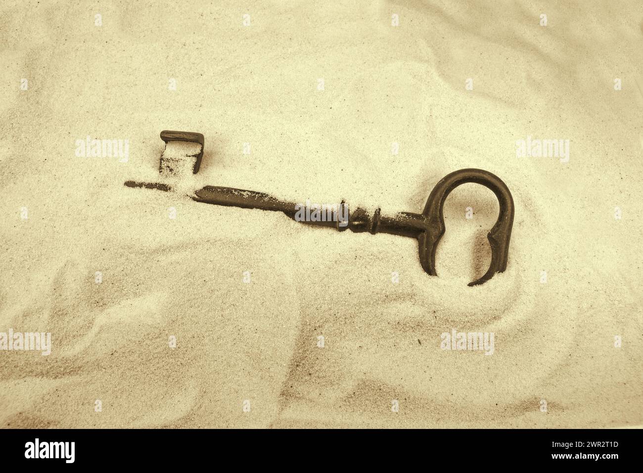 Unlock your future. Old vintage key on the sand. Forgotten, unwanted ...