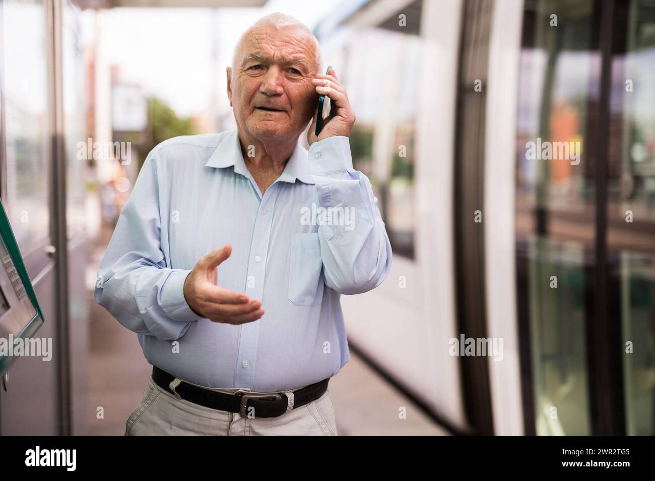 Old man talking on phone in tram station Stock Photo - Alamy