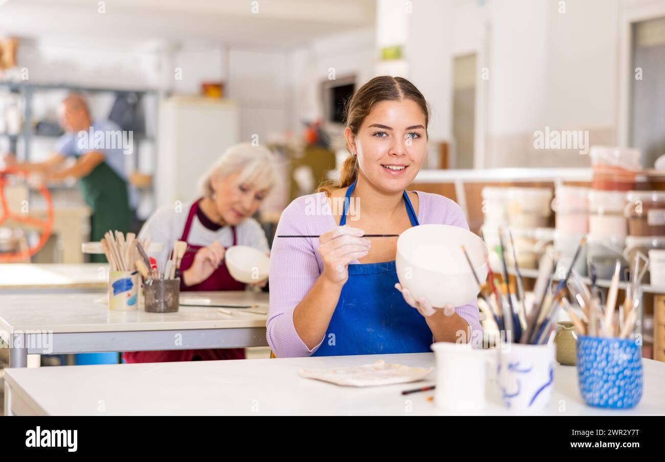 Woman learning to paint pottery at pottery class Stock Photo - Alamy
