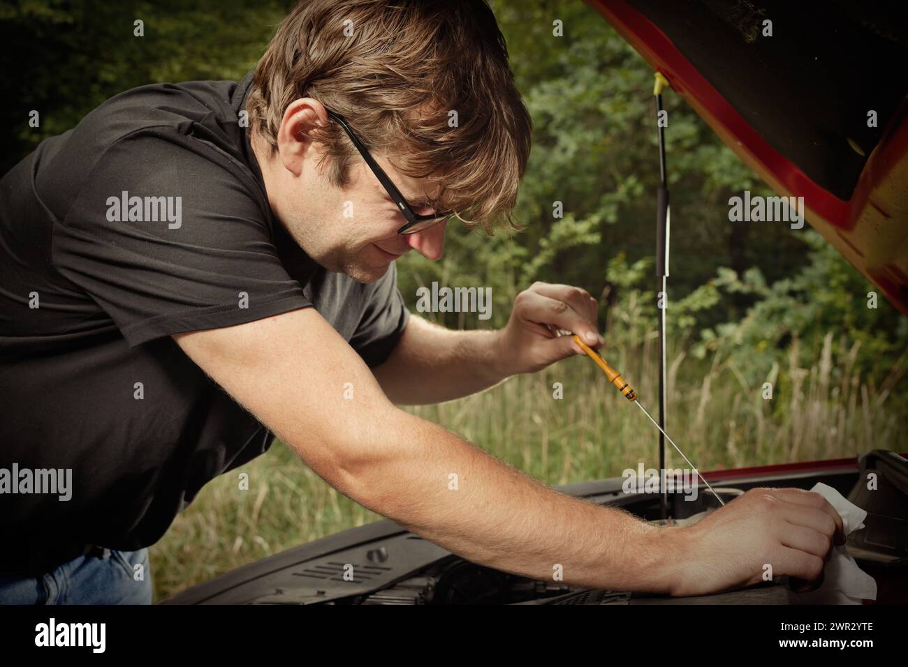 Car driver take care of his car before longer trip and checking oil ...
