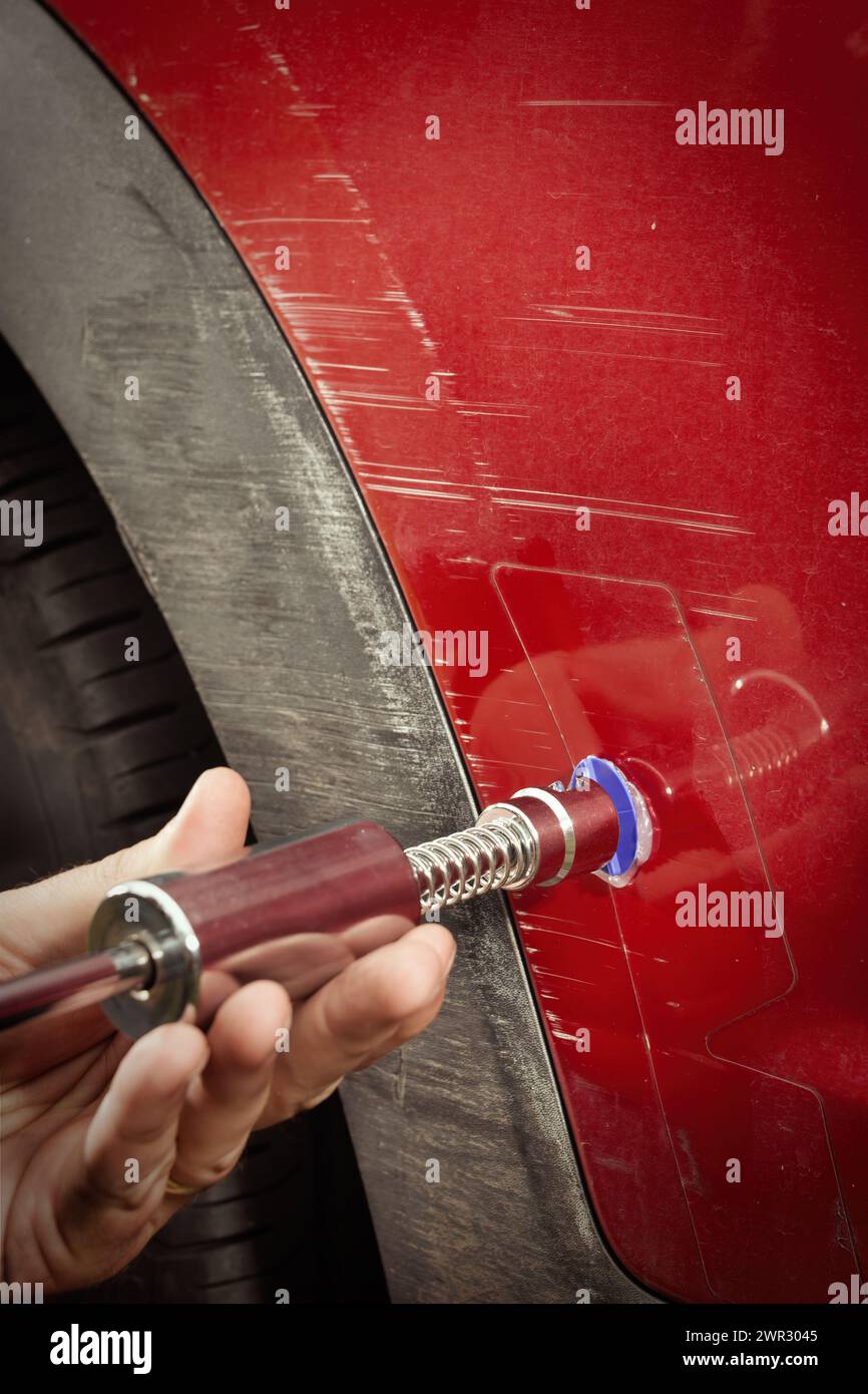 Car owner working on a dent repair with reverse hammer and glue Stock ...