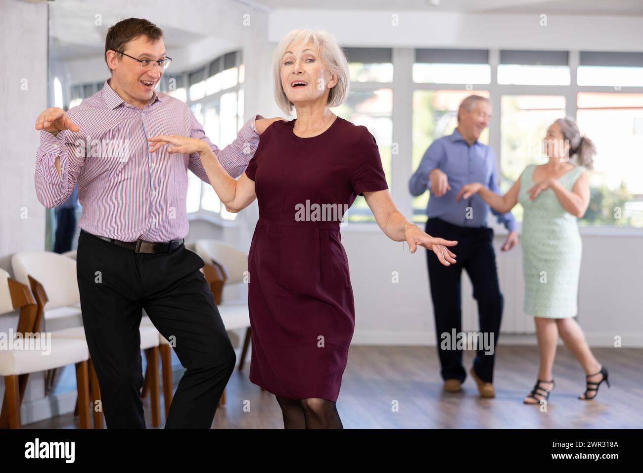 Group of adult active people practicing vogue dancing movements while ...