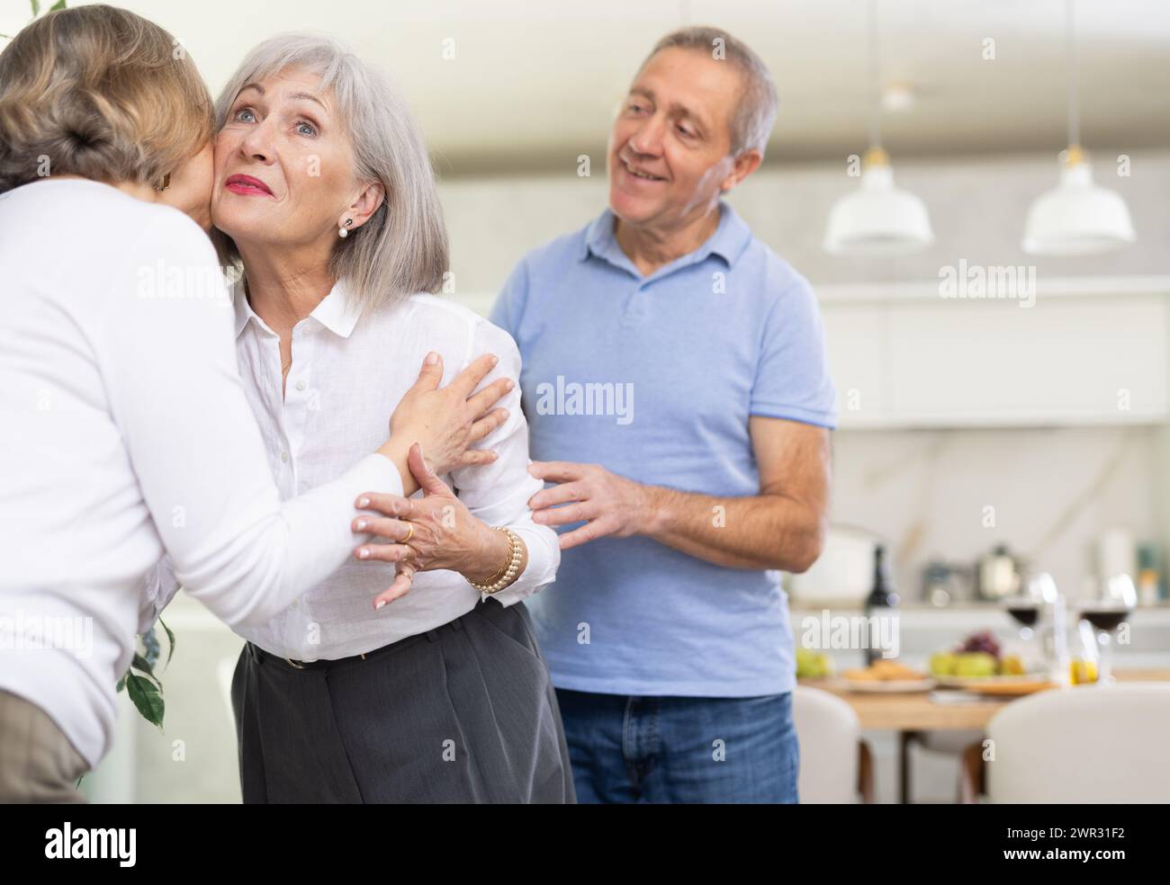 As two elderly woman meet, they exchange warm greeting by embracing ...