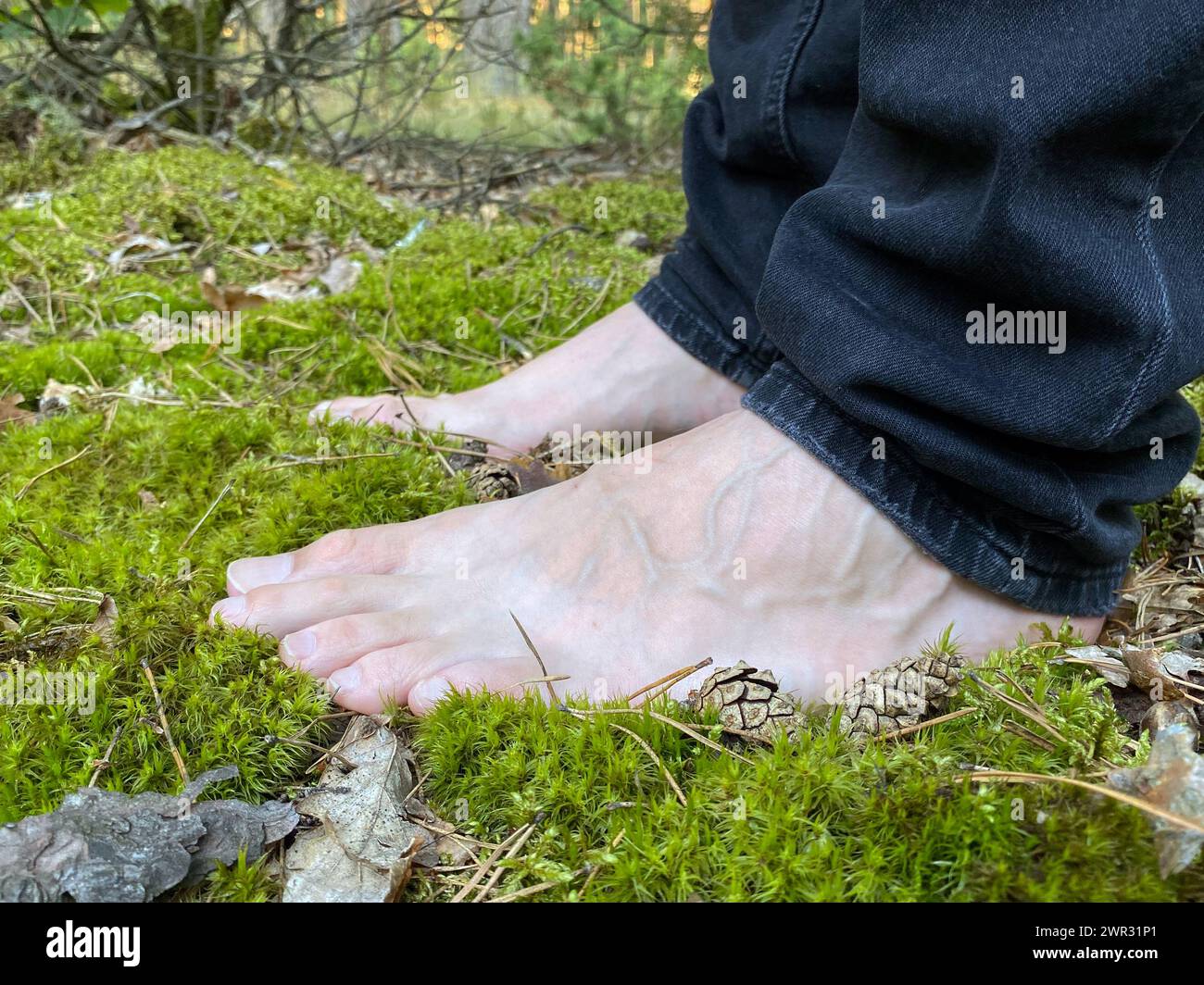 Human is barefoot in the forest. Feet are on soft moss, close up ...
