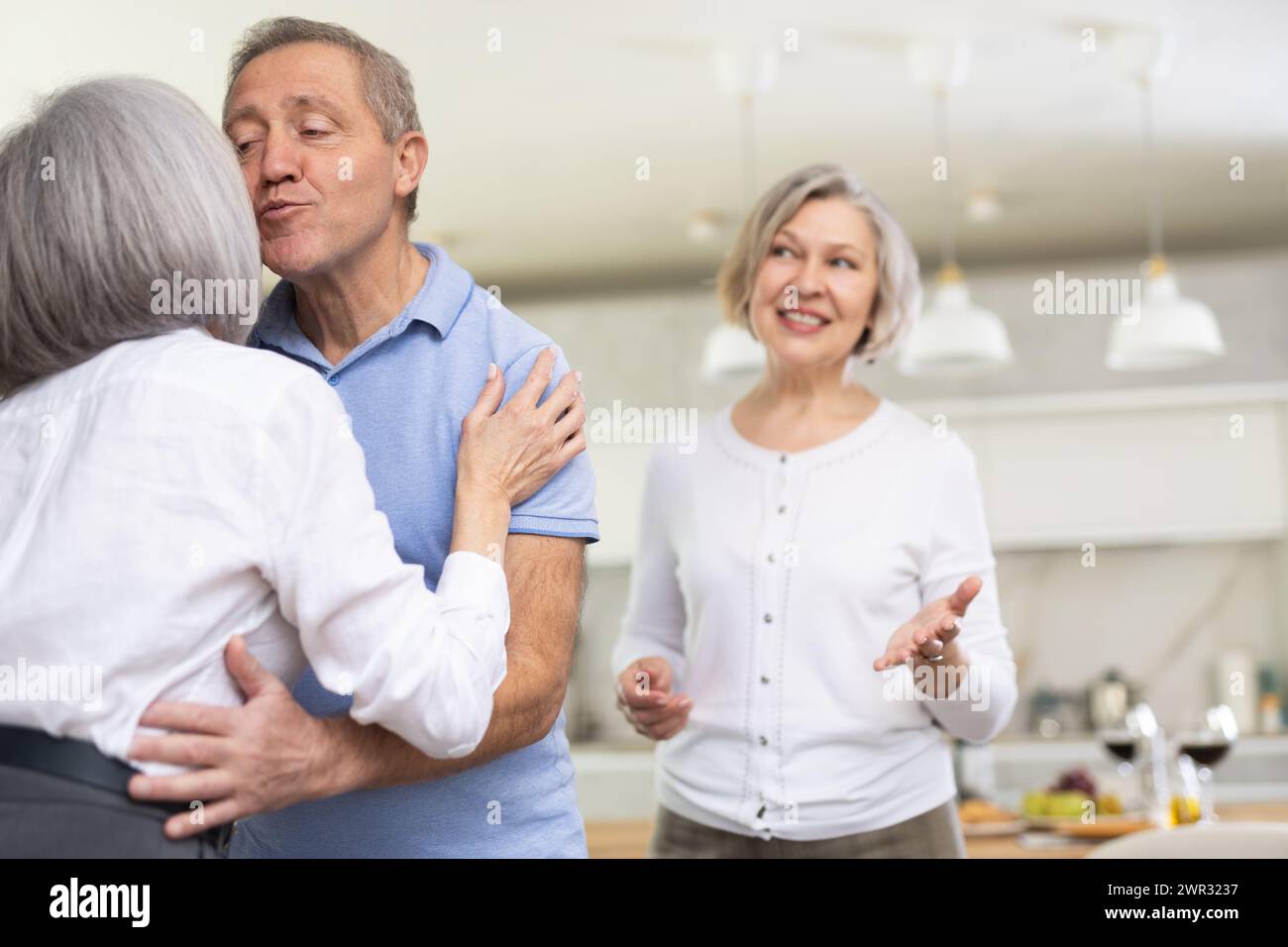 Two elderly couples meet for holiday dinner at home. Greet each other ...