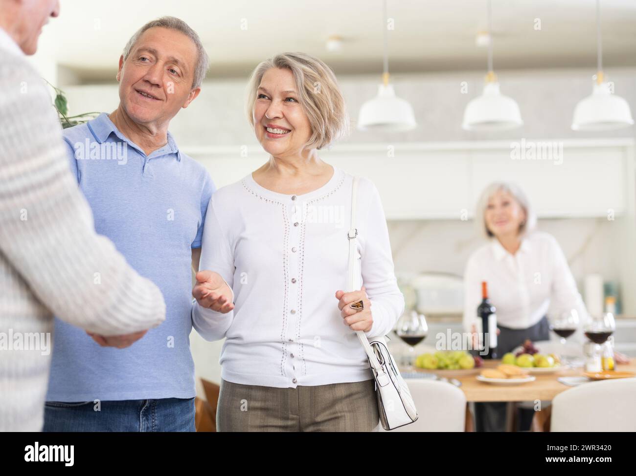 Two elderly couples meet for holiday dinner at home. Greet each other ...