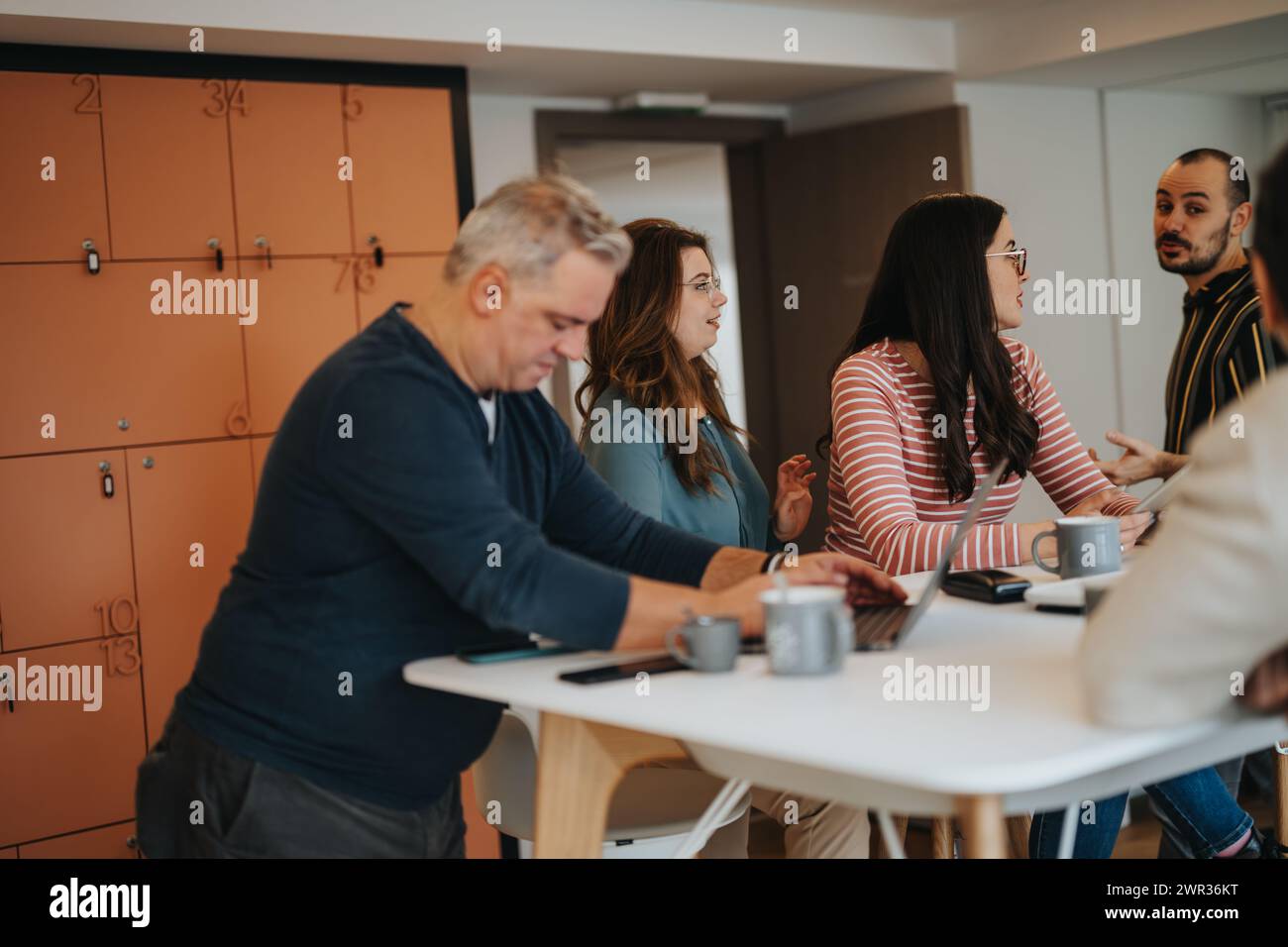 A different aged group of company employees engage in a collaborative ...