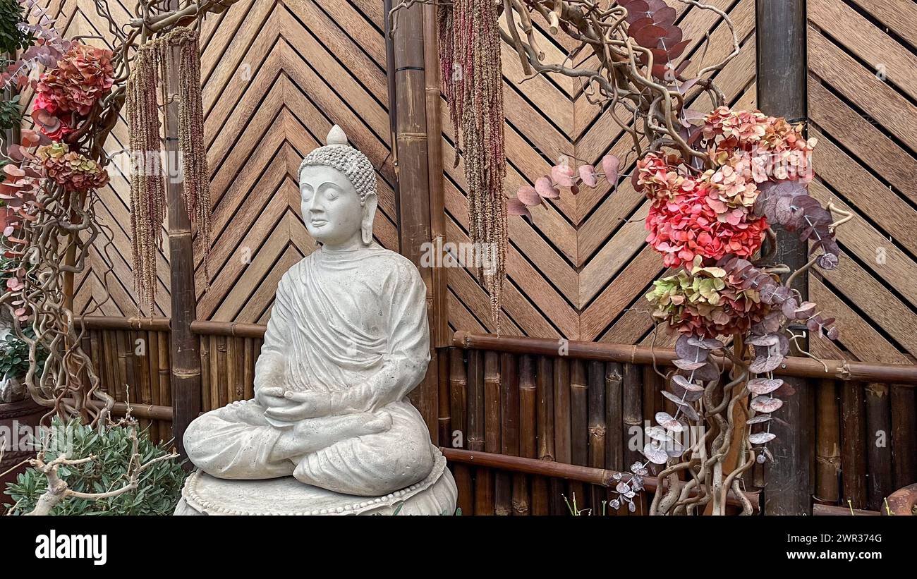 Stone Buddha figure sitting in an indoor garden with a background of ...
