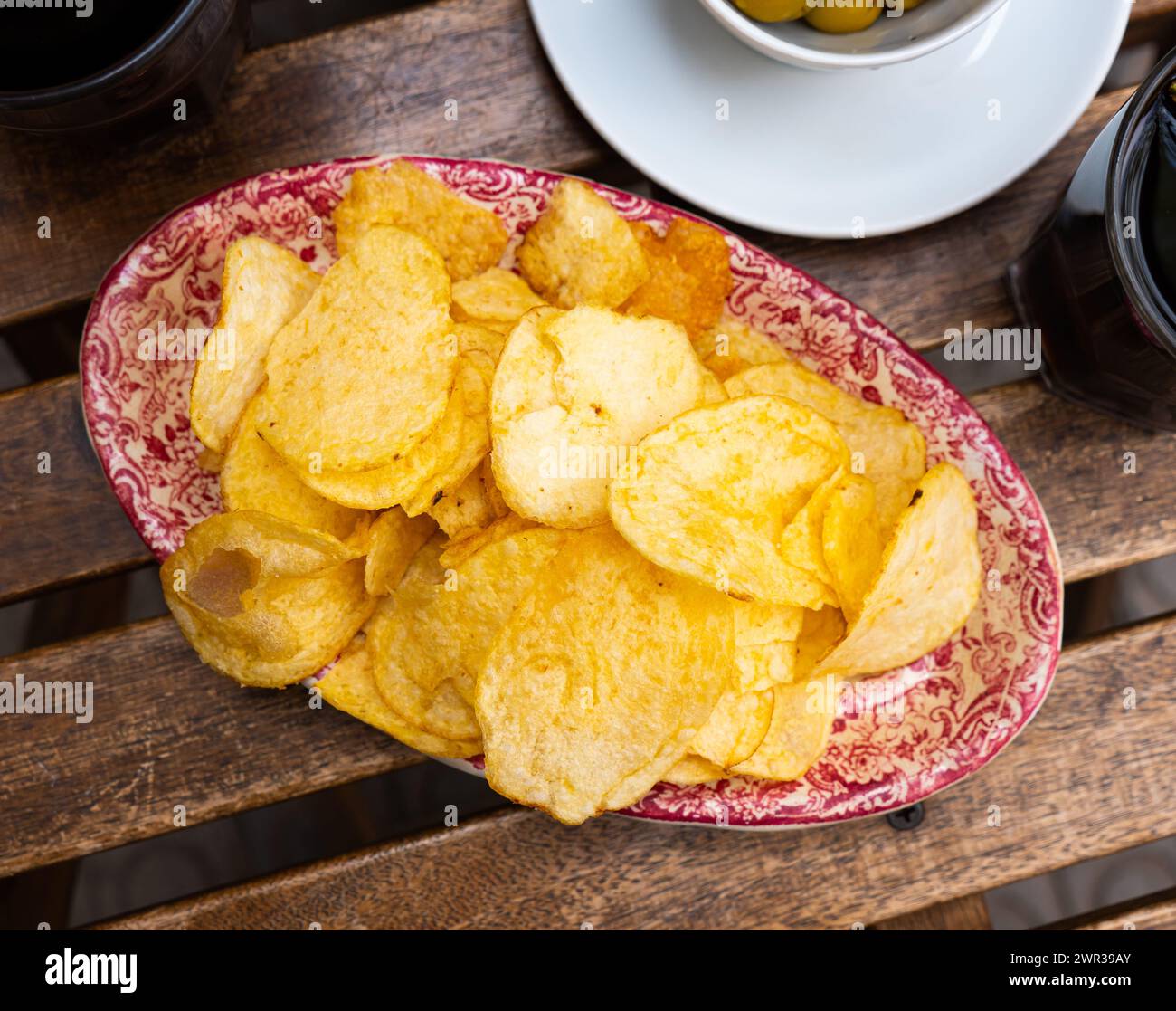 Pile of crispy potato chips on plate served with red vermouth Stock ...