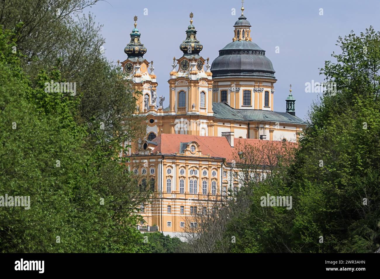 Baroque abbey surrounded by green trees with gold-decorated towers and ...