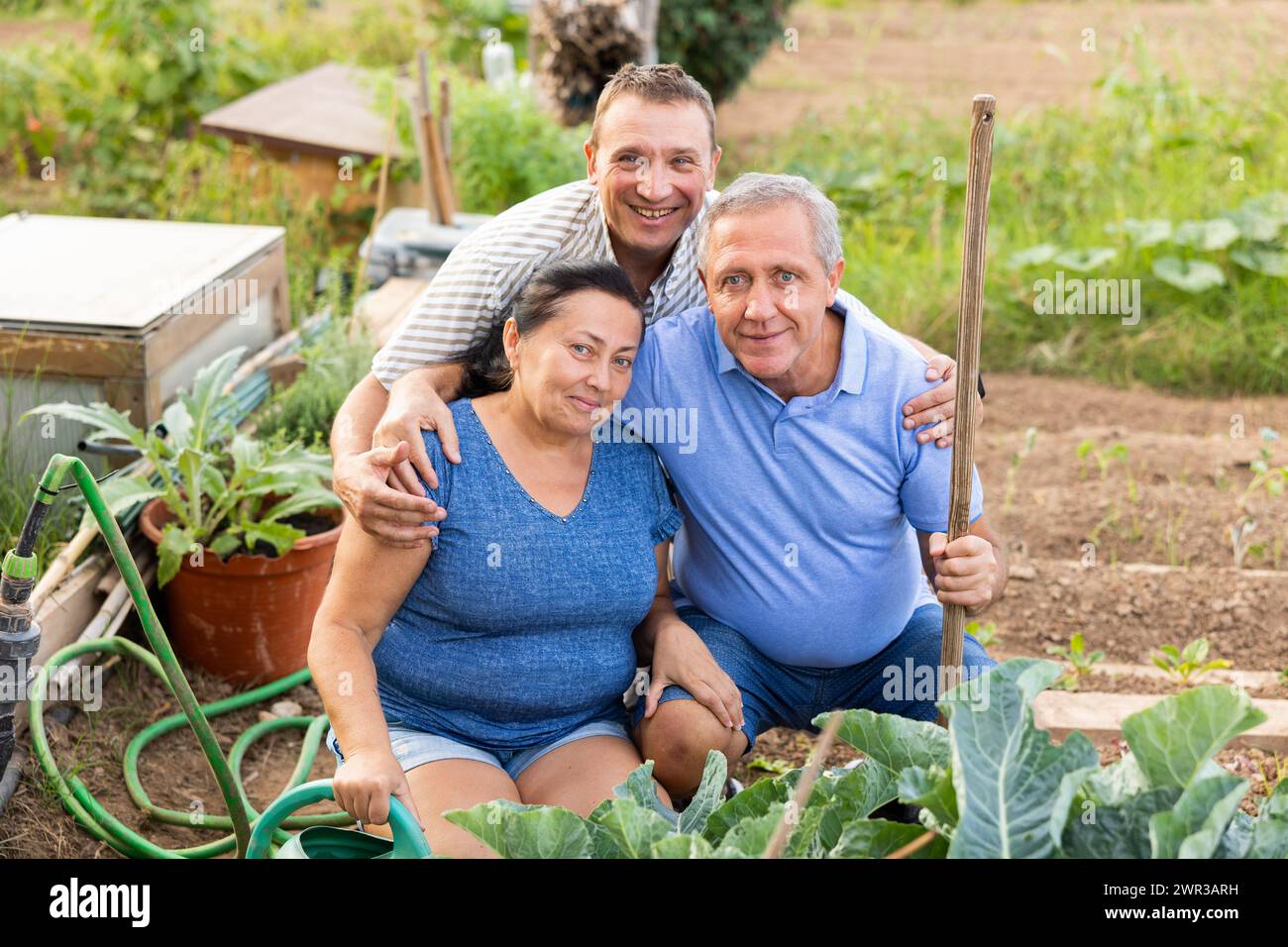 Happy elderly couple with adult son posing in homestead garden Stock ...
