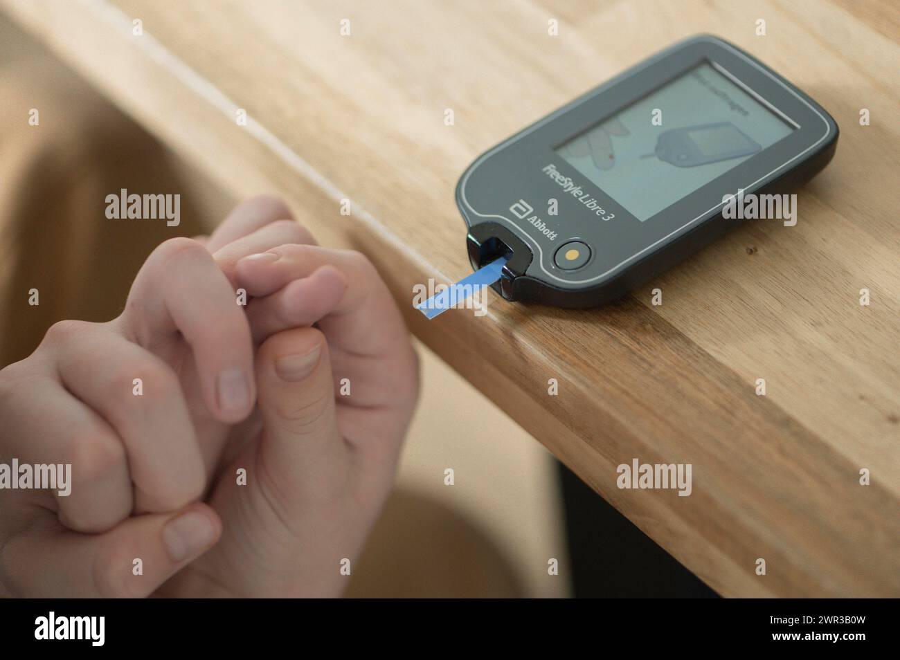 Blood glucose meter with test strips lying on a wooden table, child's ...