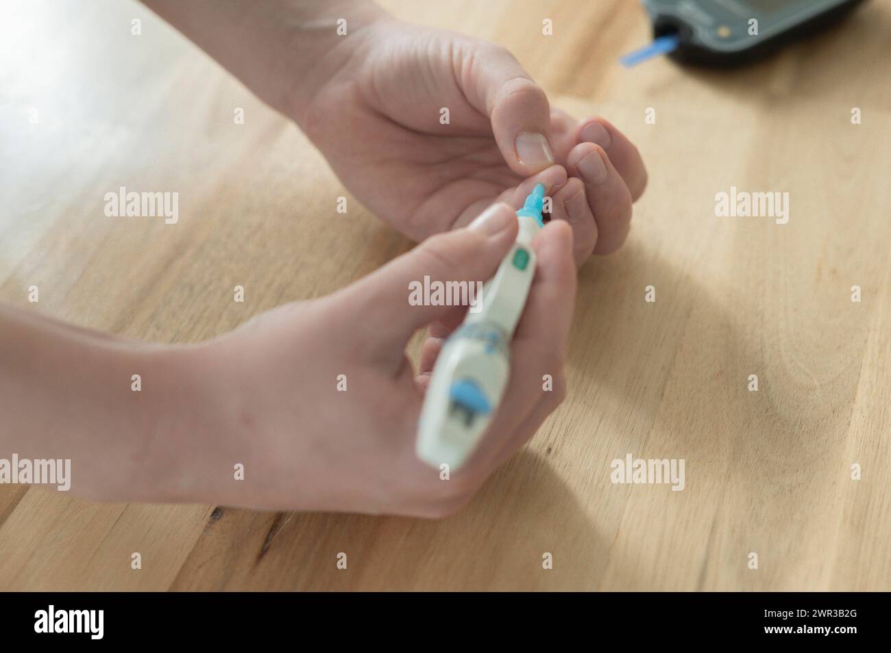 A lancet, lancing device, is held by a child in the right hand, pricks ...