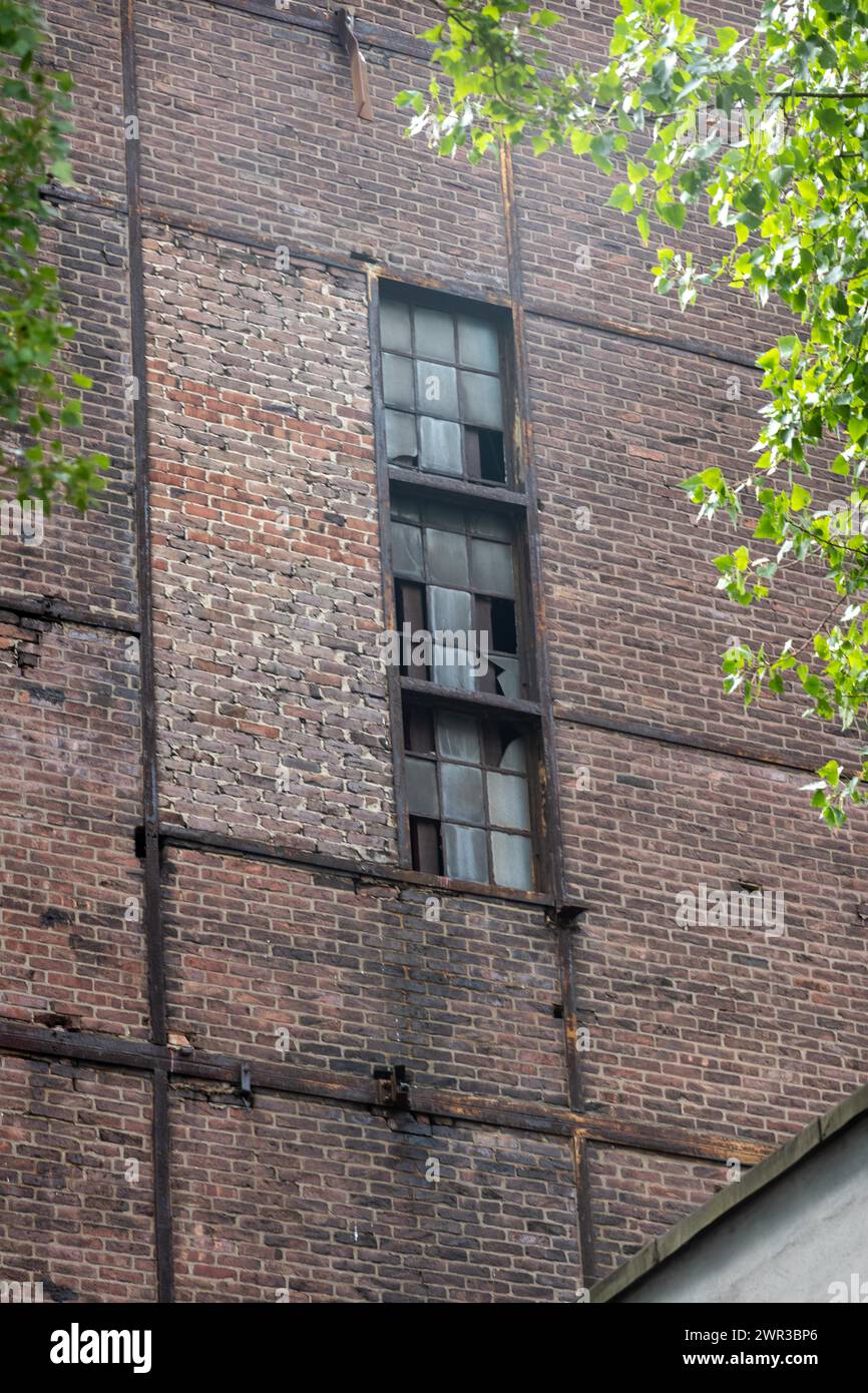 Facade of a dilapidated brick building with long, narrow windows Stock ...