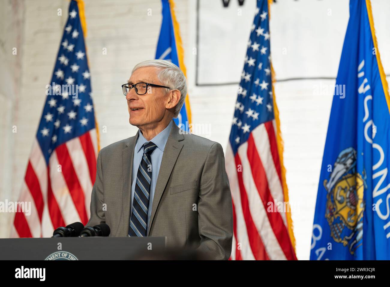 Wisconsin Governor Tony Evers gives a speech with American flags behind ...