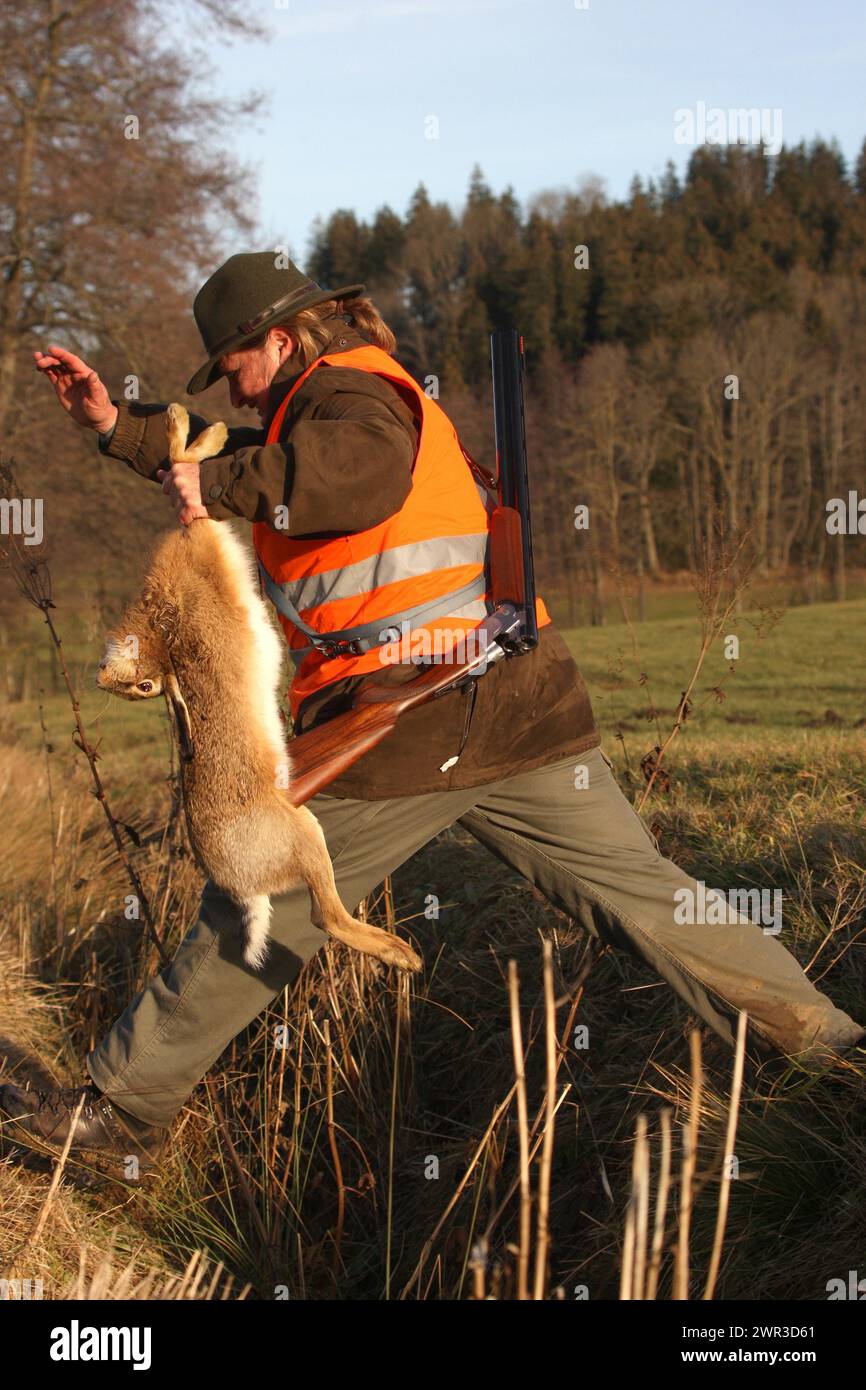 Huntress with safety waistcoat and hunted hare (Lepus europaeus ...