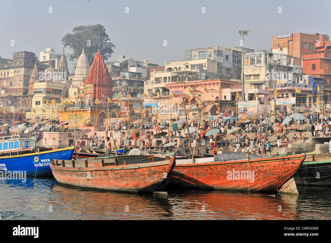 Lively riverside landscape with crowds of people and boats in the hazy ...