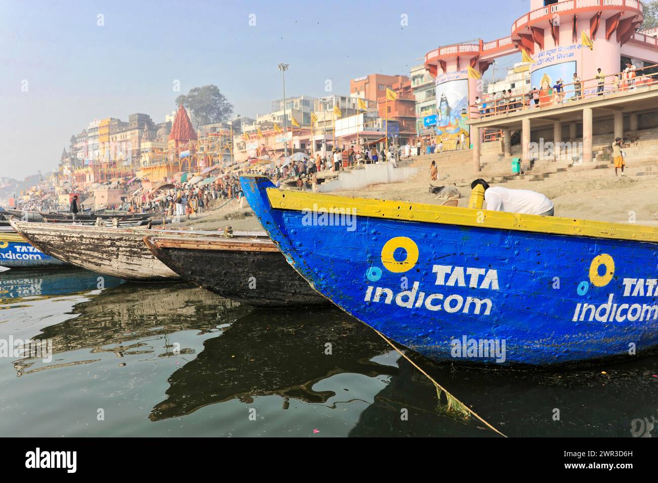 Boats on the banks of a busy river with colourful buildings in the ...