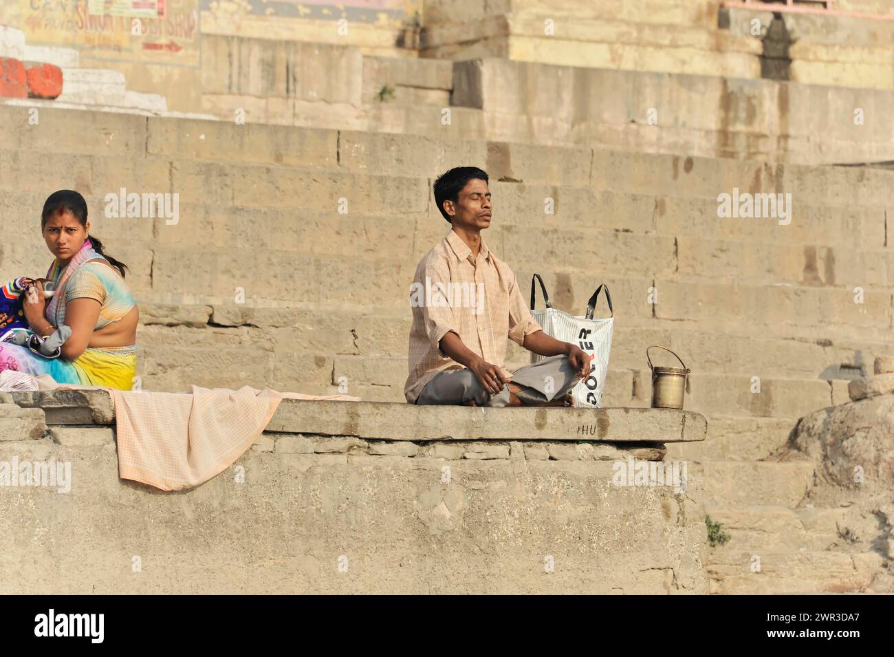 Single person praying on the steps of the ghats in the morning light ...