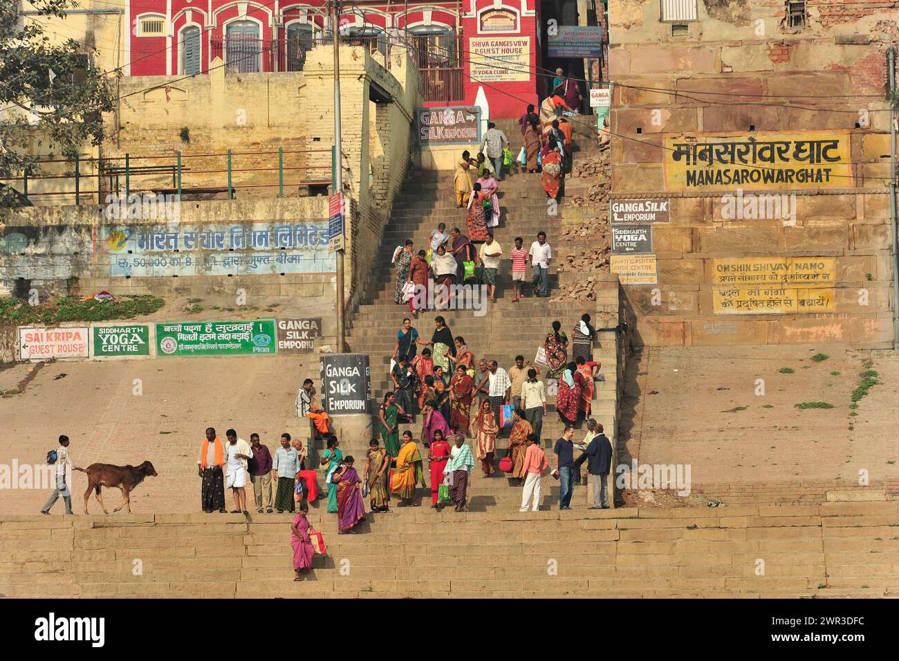 A group of people in traditional dress gather on a riverbank with yoga ...