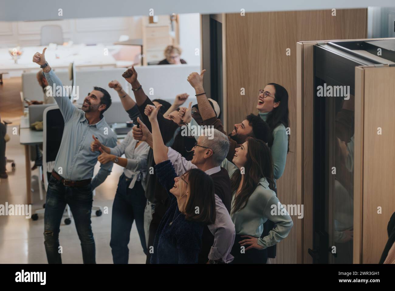 Group of joyful colleagues in a modern office cheering a business ...