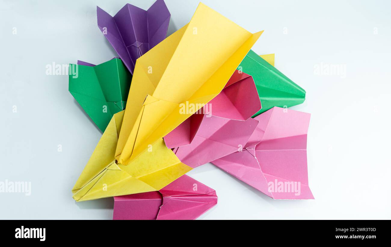 Pile of pink, purple, green and yellow paper airplanes isolated on ...