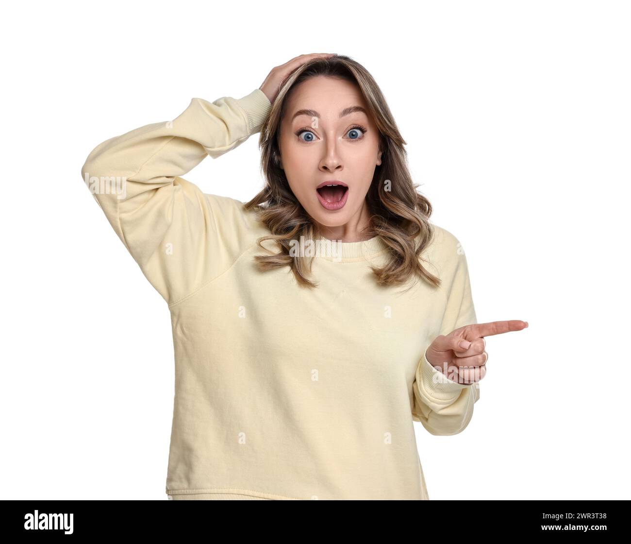 Portrait of surprised woman pointing at something on white background ...