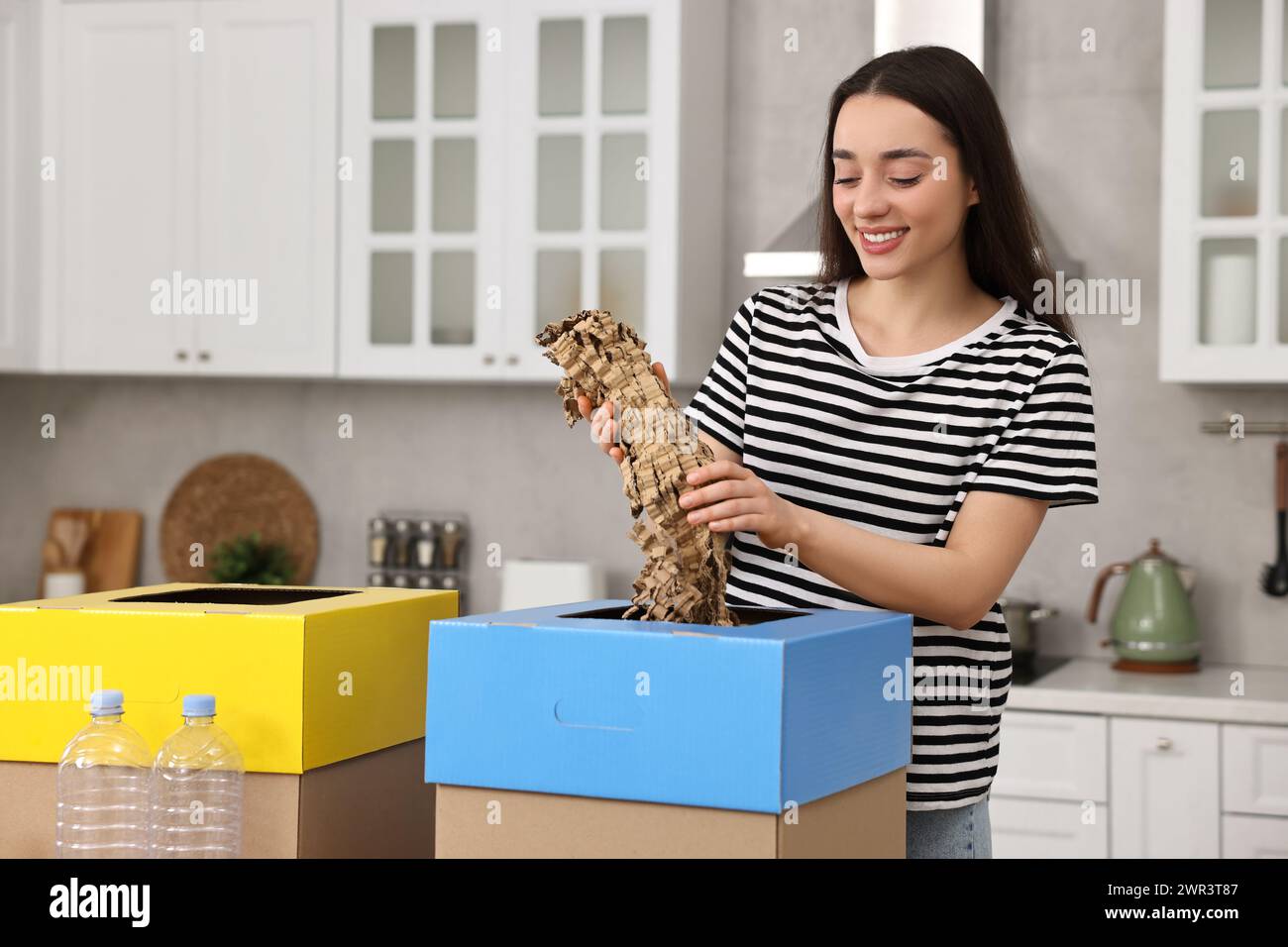Garbage sorting. Smiling woman throwing shredded paper into cardboard ...
