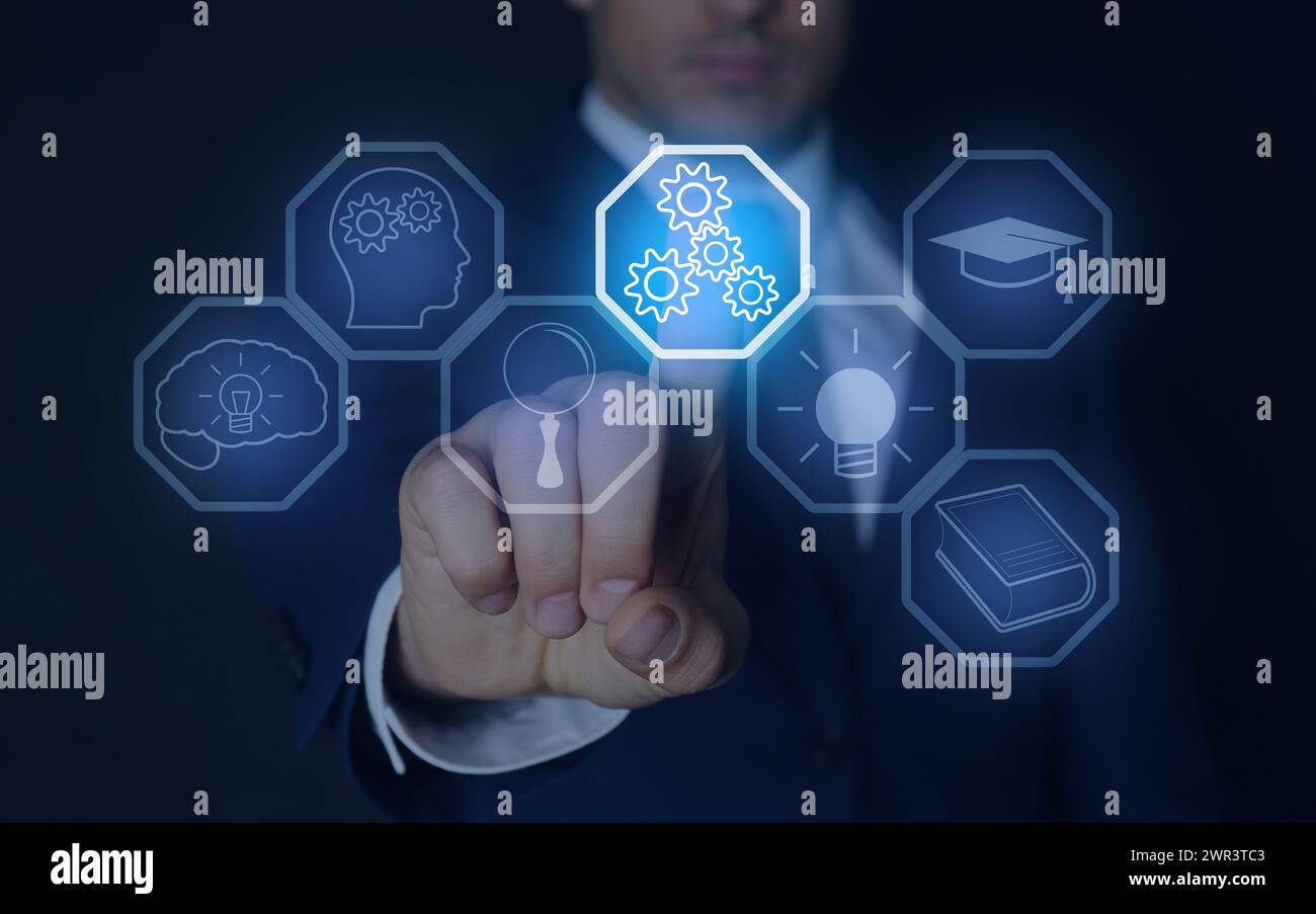 E-learning. Man using virtual screen with different icons on dark ...