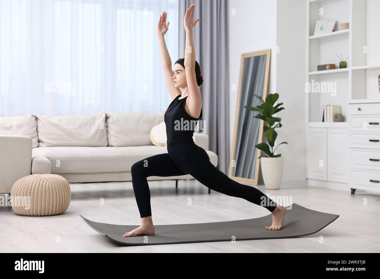 Girl practicing crescent asana on yoga mat at home. High lunge pose ...