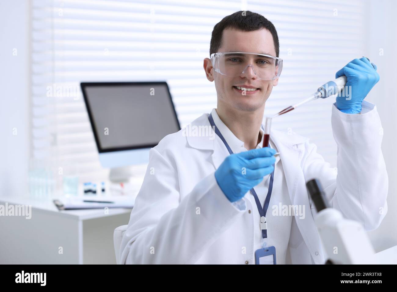Scientist dripping sample into test tube in laboratory Stock Photo - Alamy