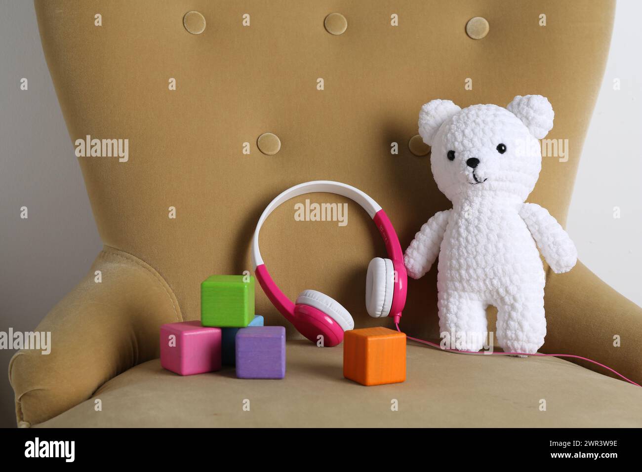 Baby songs. Toy bear, headphones and cubes on armchair Stock Photo - Alamy