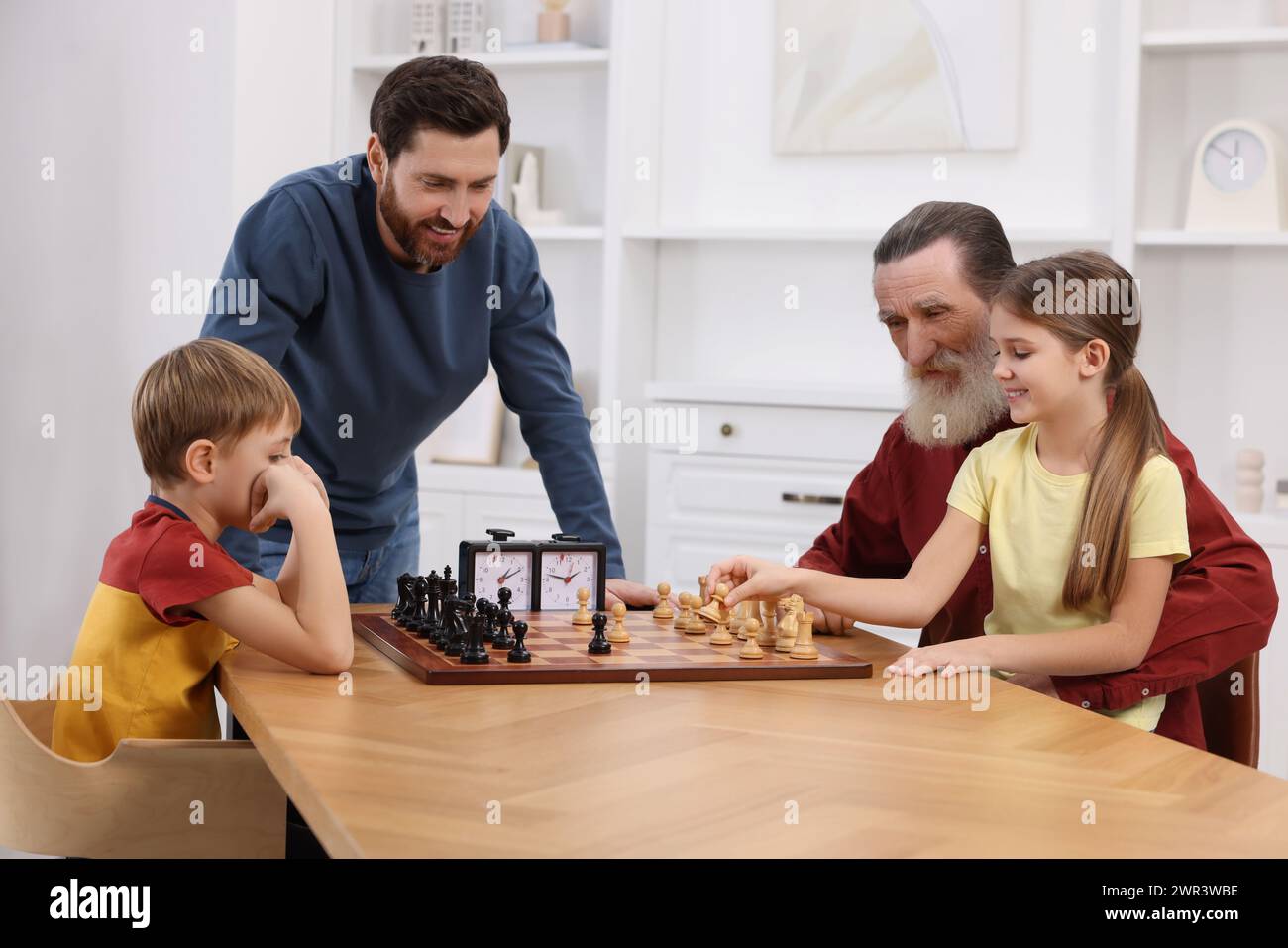 Family playing chess together at table in room Stock Photo - Alamy