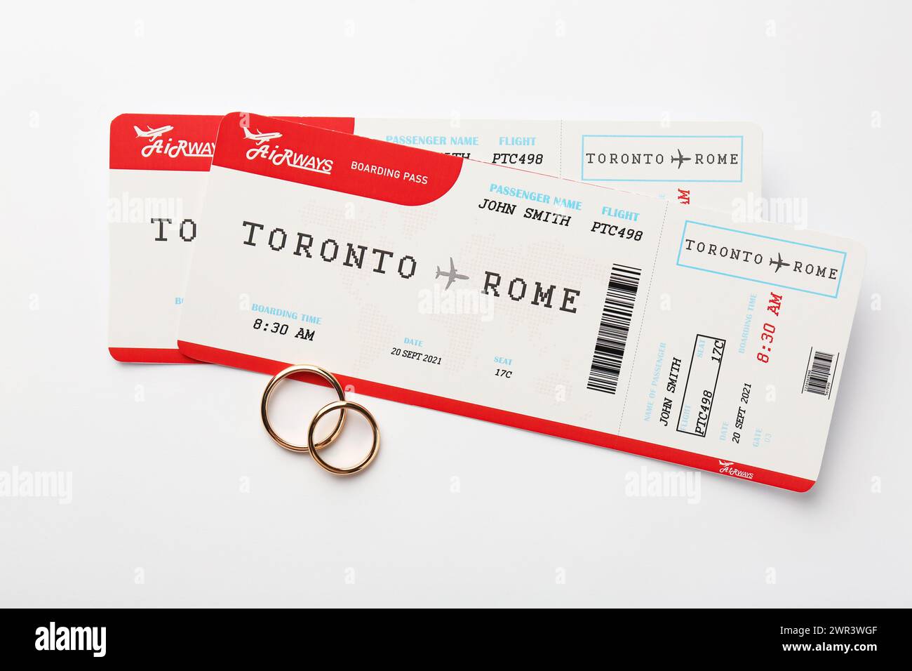 Honeymoon concept. Plane tickets and two golden rings on white ...