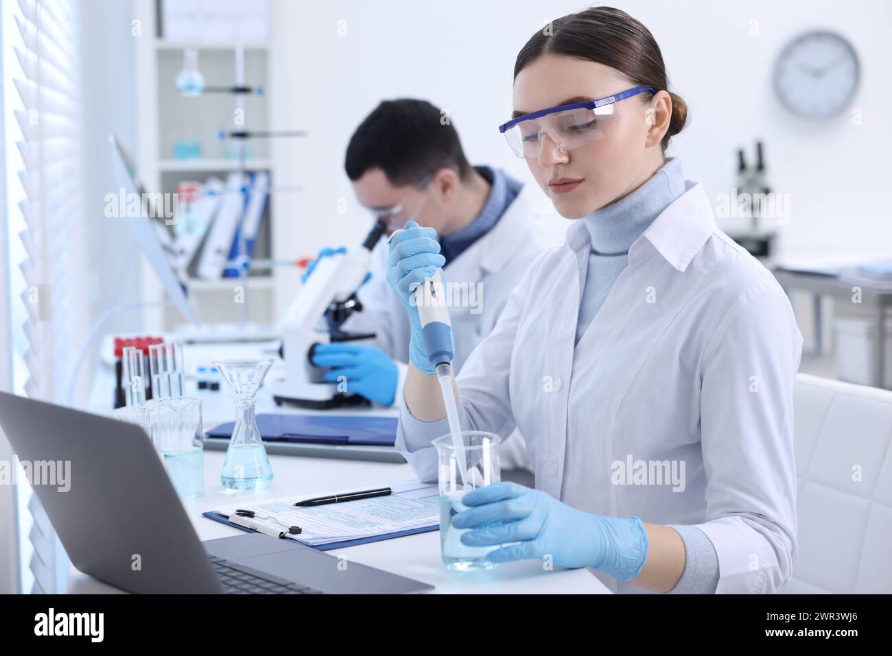 Scientist dripping sample into beaker in laboratory Stock Photo - Alamy