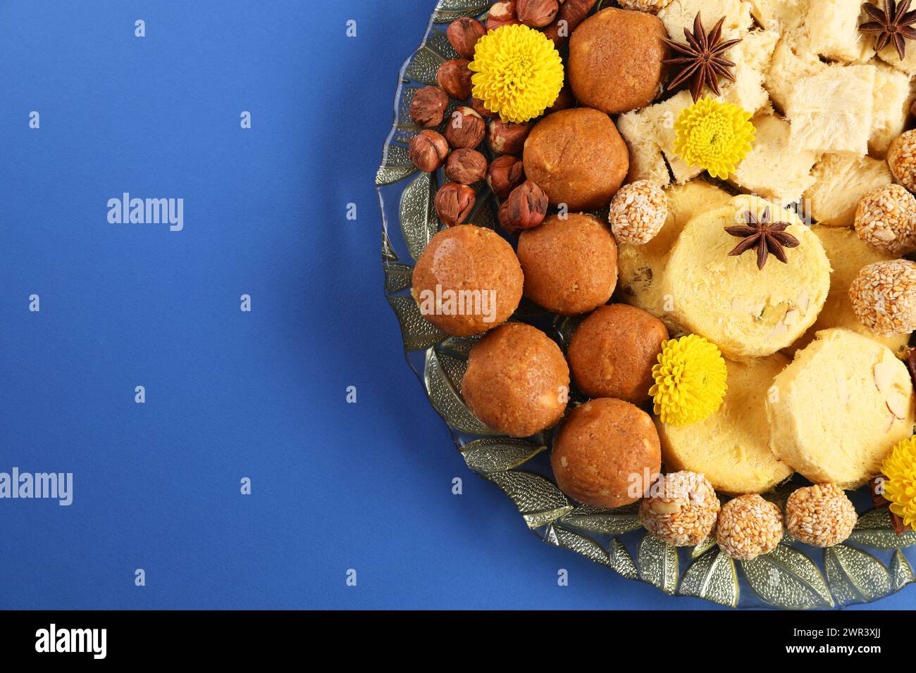 Diwali celebration. Tasty Indian sweets, spices and nuts on blue table ...