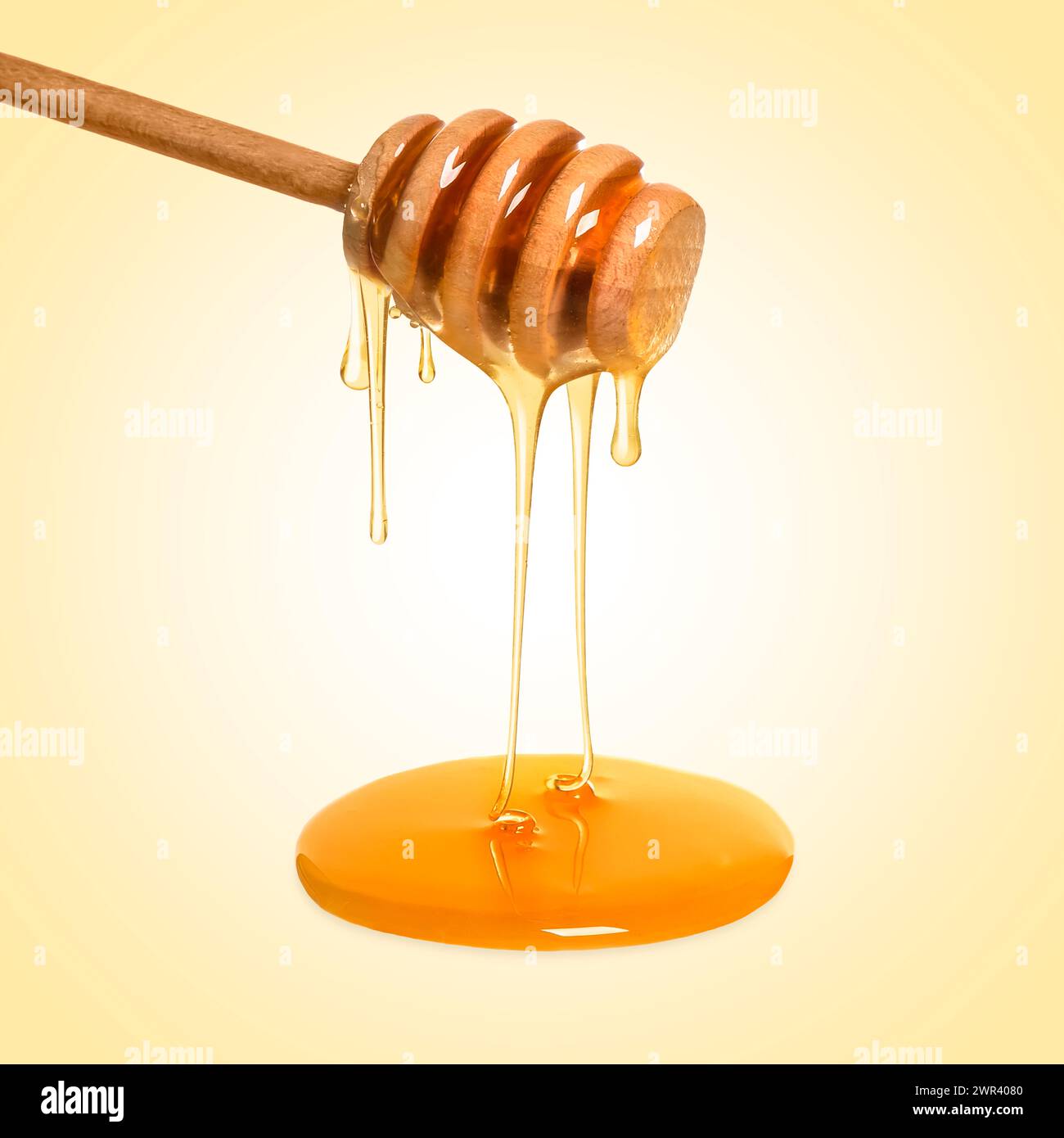 Natural honey dripping from dipper on pale yellow background Stock ...