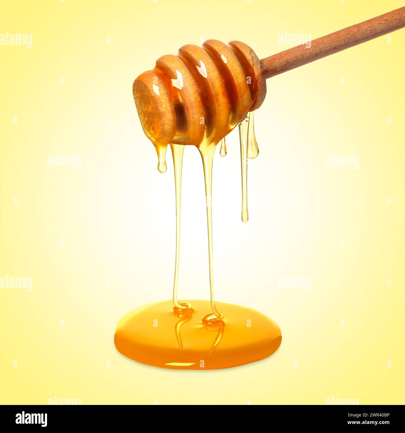 Natural honey dripping from dipper on yellow background Stock Photo - Alamy